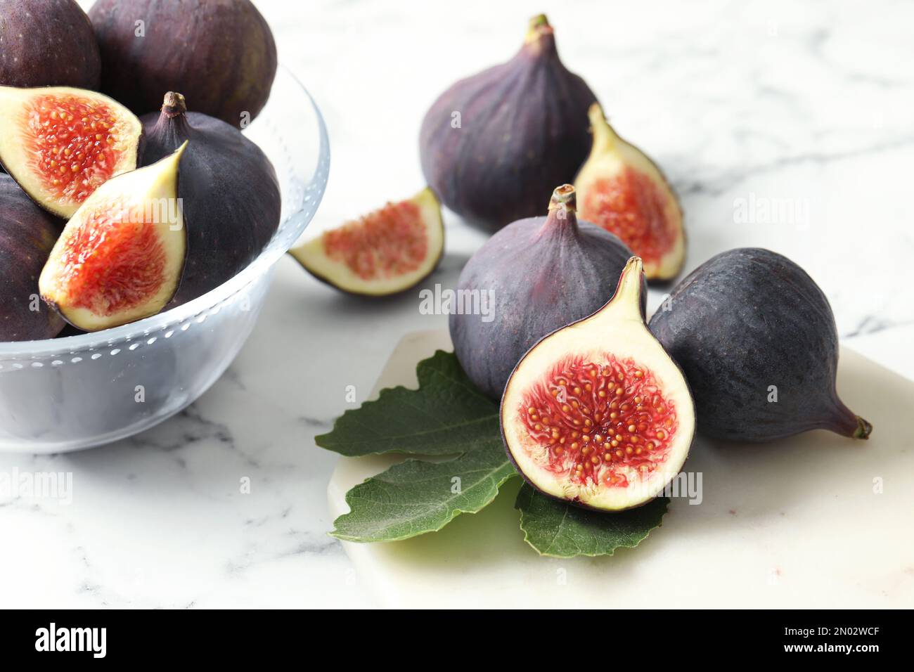 Whole and cut tasty fresh figs on white marble table Stock Photo - Alamy