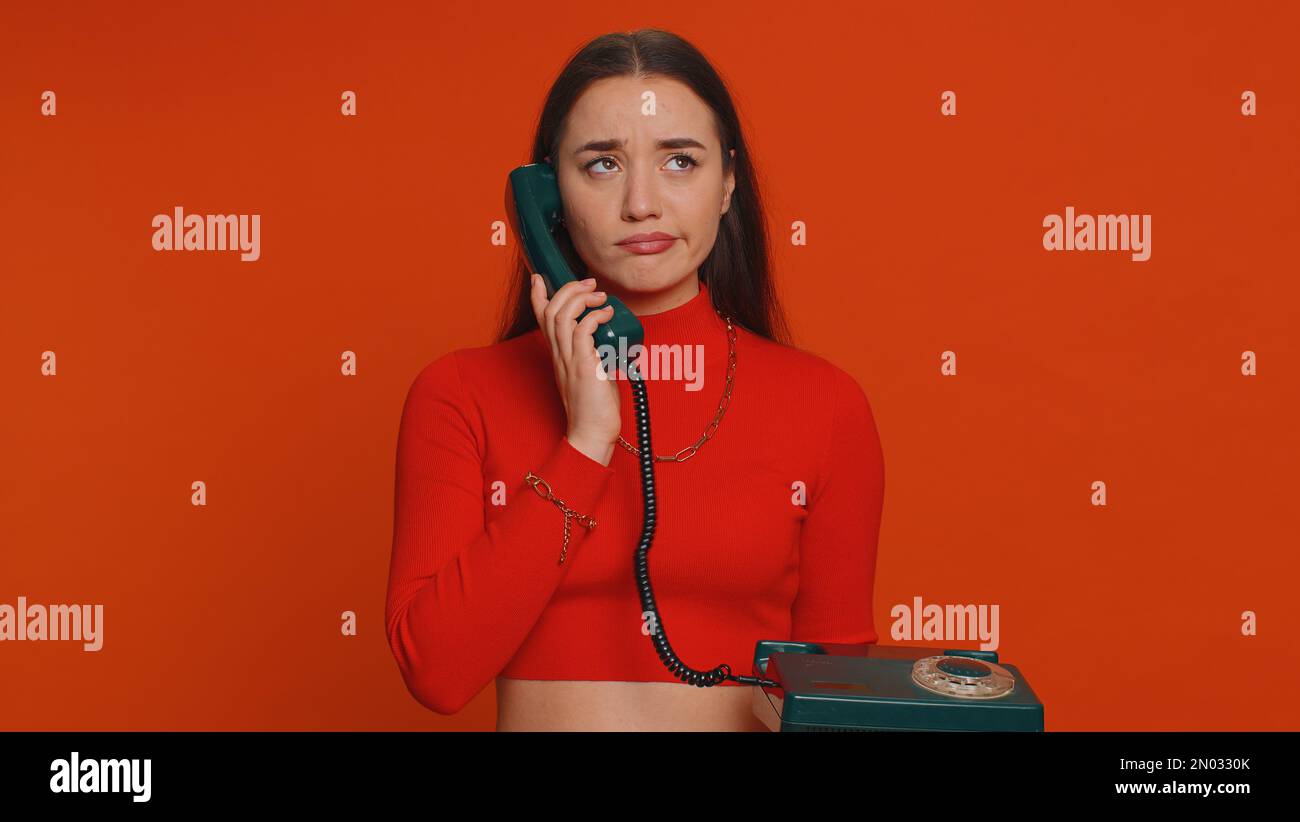 Bored, tired pretty young woman in crop top talking on wired vintage ...