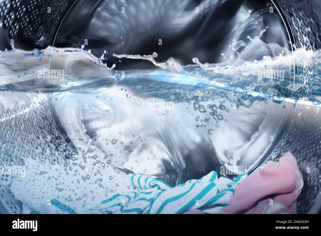Washing machine drum with water and clothes, closeup view Stock Photo ...