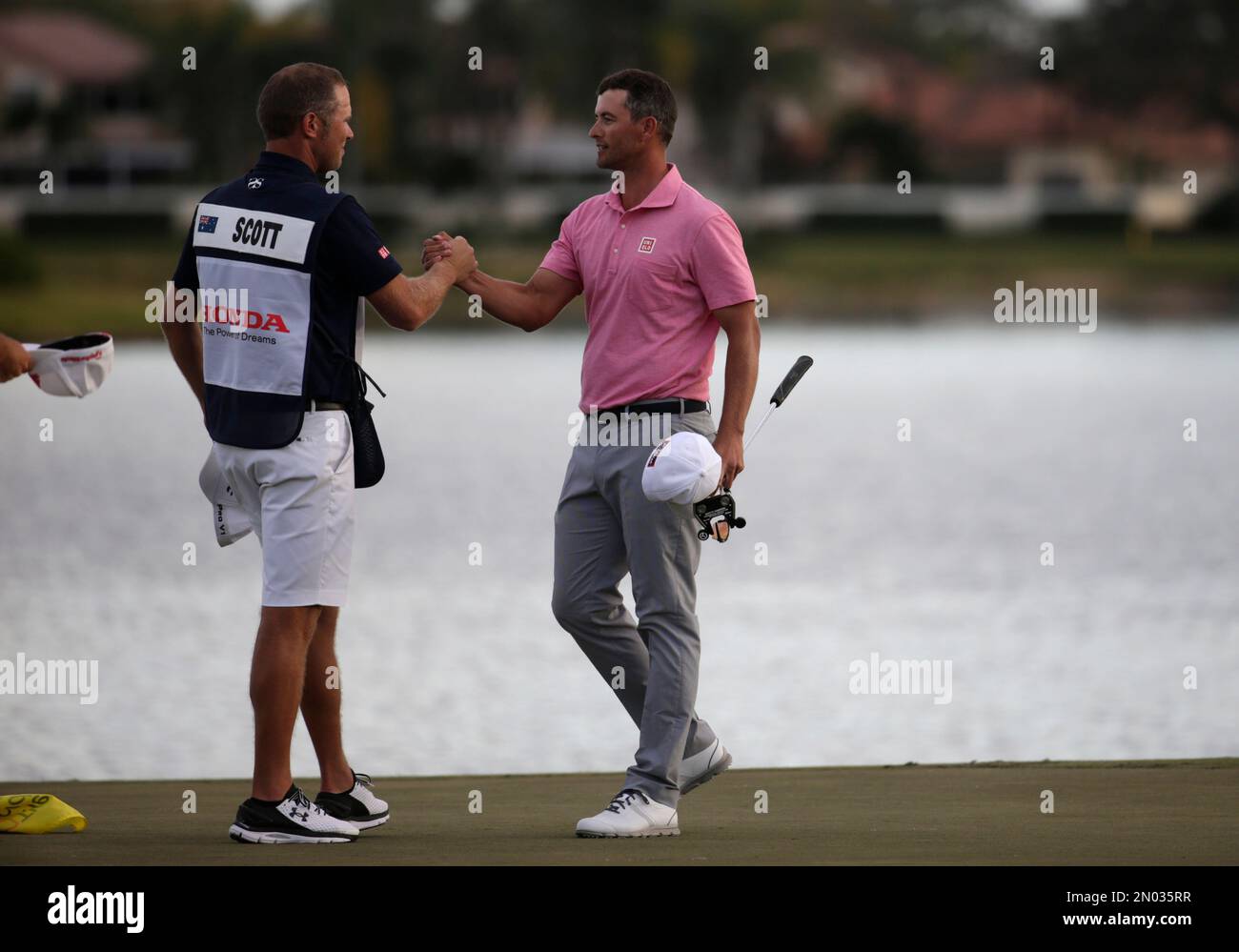 Adam Scott, of Australia, right, shakes hands with his caddie David ...