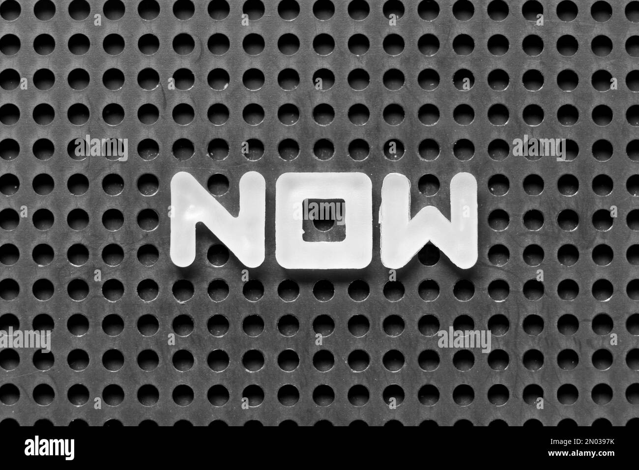 White alphabet letter in word now on black pegboard background Stock ...
