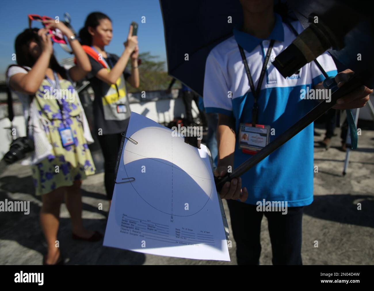 Filipino students observe as the partial solar eclipse is reflected on ...