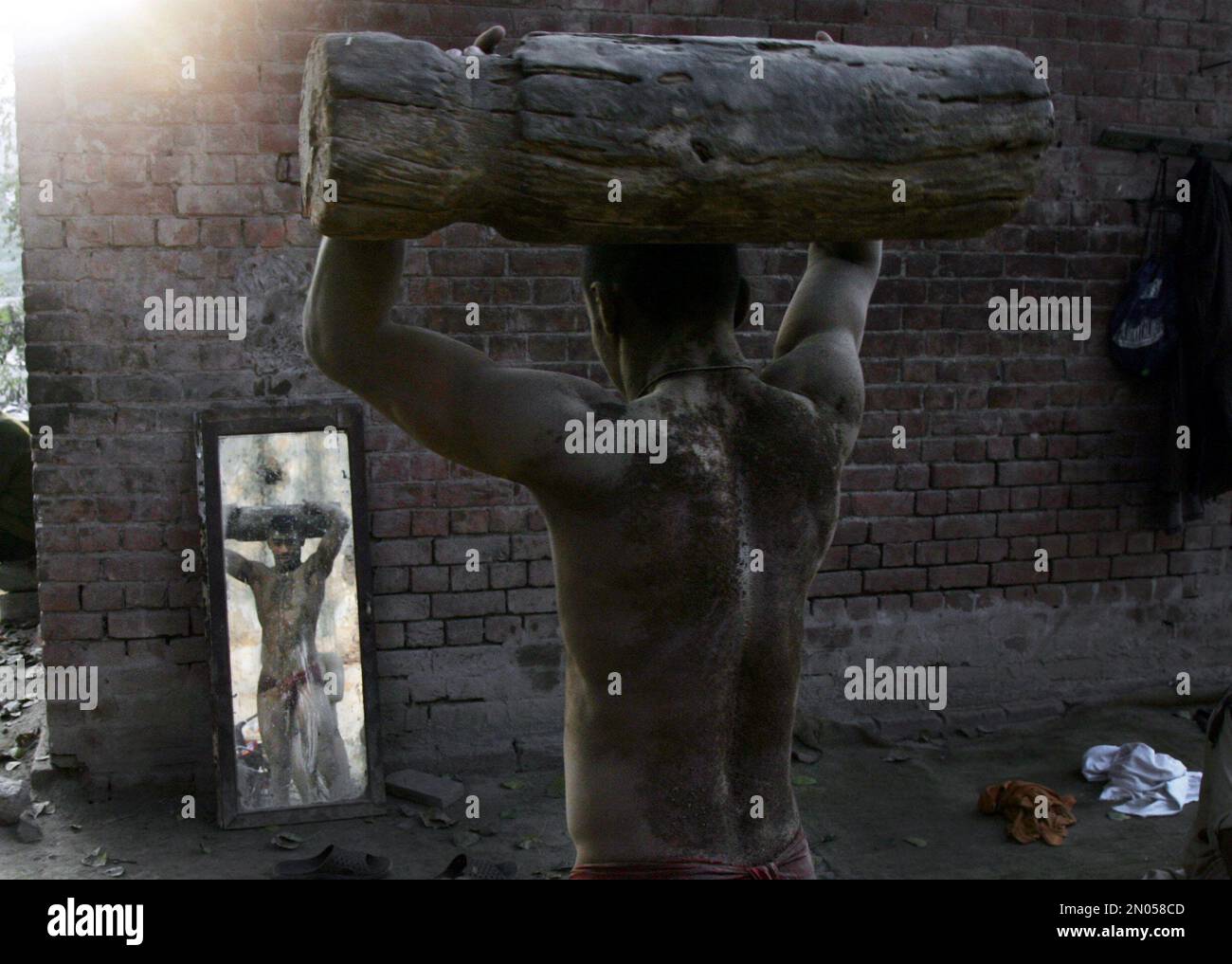 A Pakistani Kushti wrestler looks at himself in a mirror during a ...