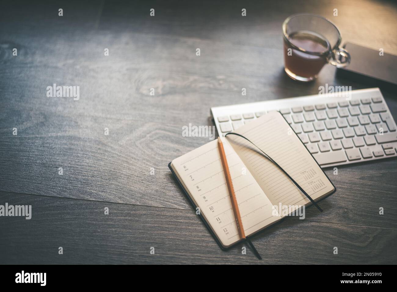 Desktop view with keyboard pencil agenda and technology devices. Table ...