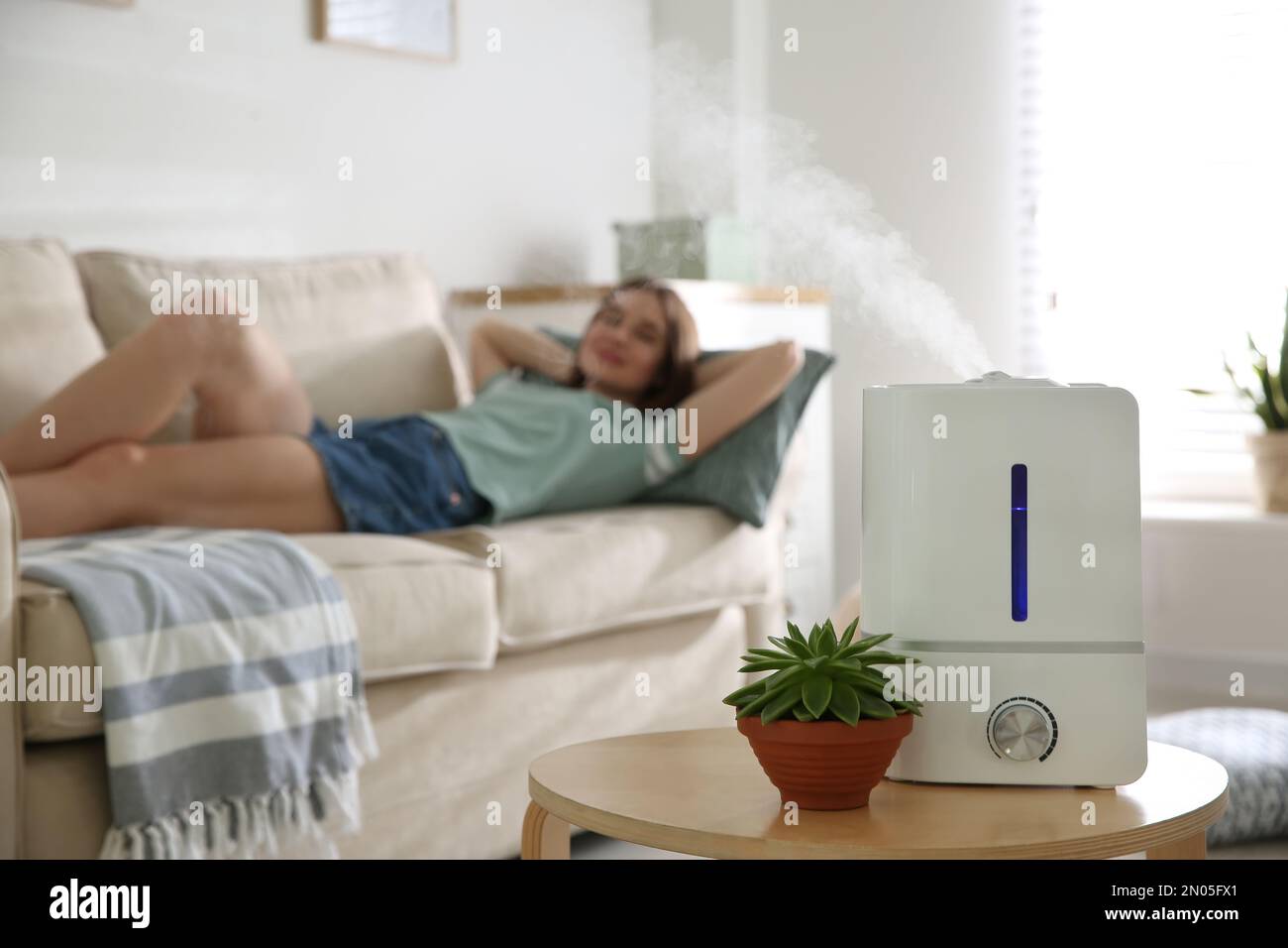 Modern air humidifier and blurred woman resting on background Stock ...