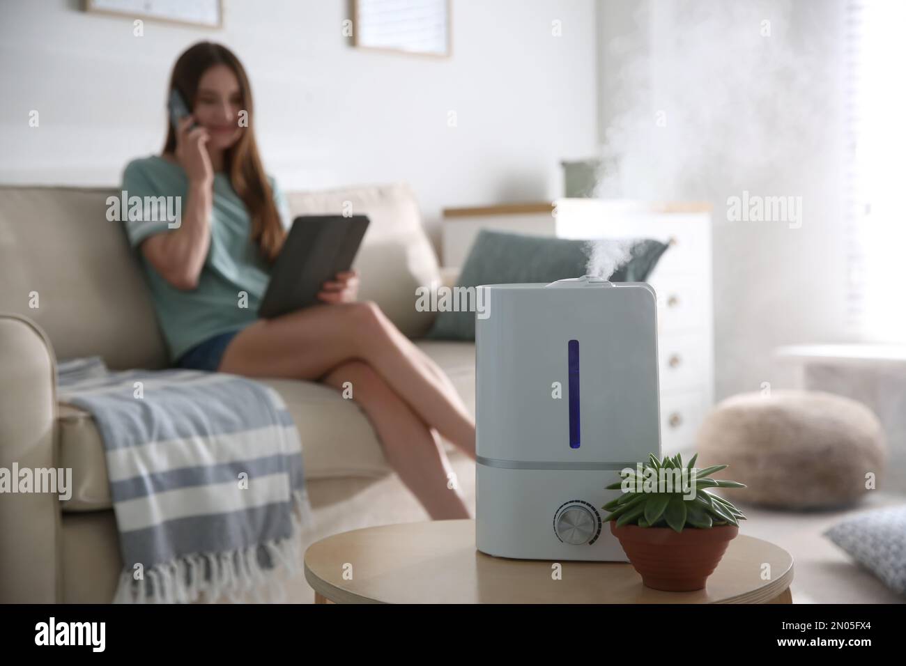 Modern air humidifier and blurred woman on background Stock Photo - Alamy