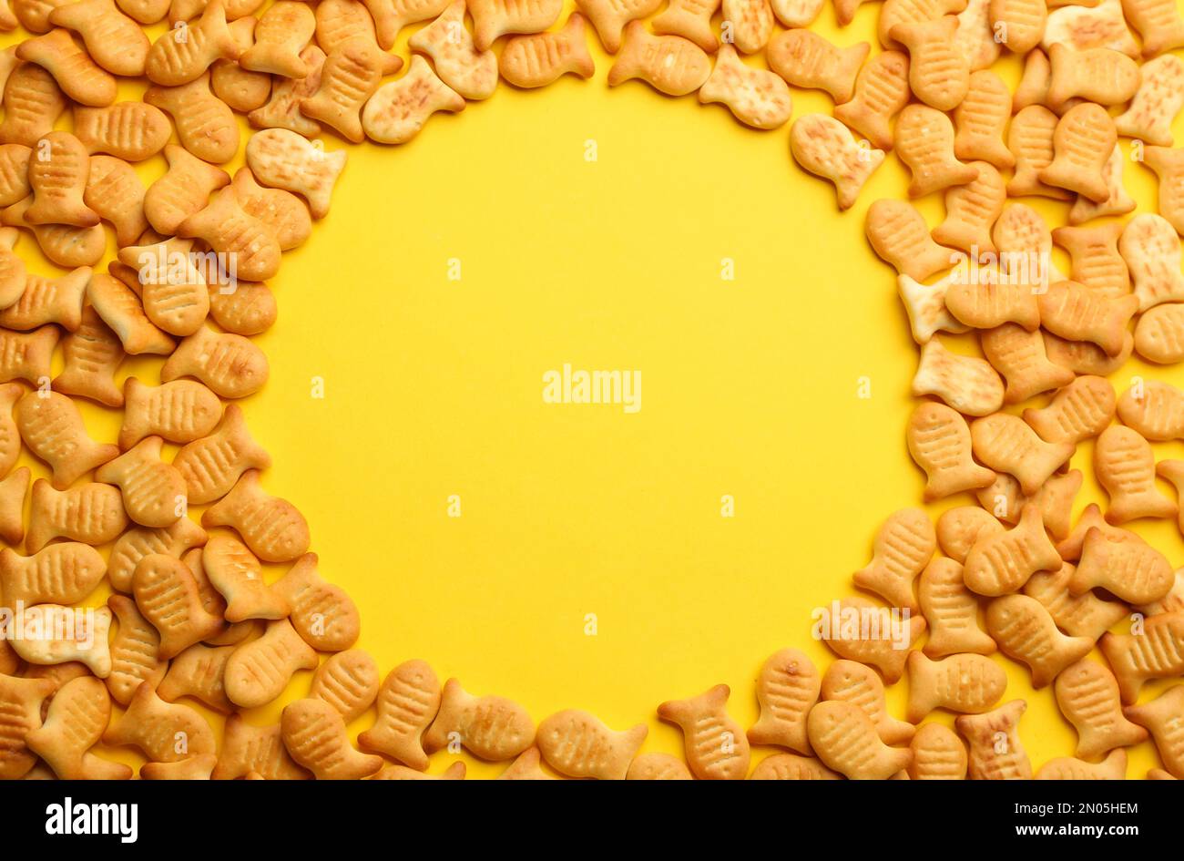 Frame of delicious goldfish crackers on yellow background, flat lay ...