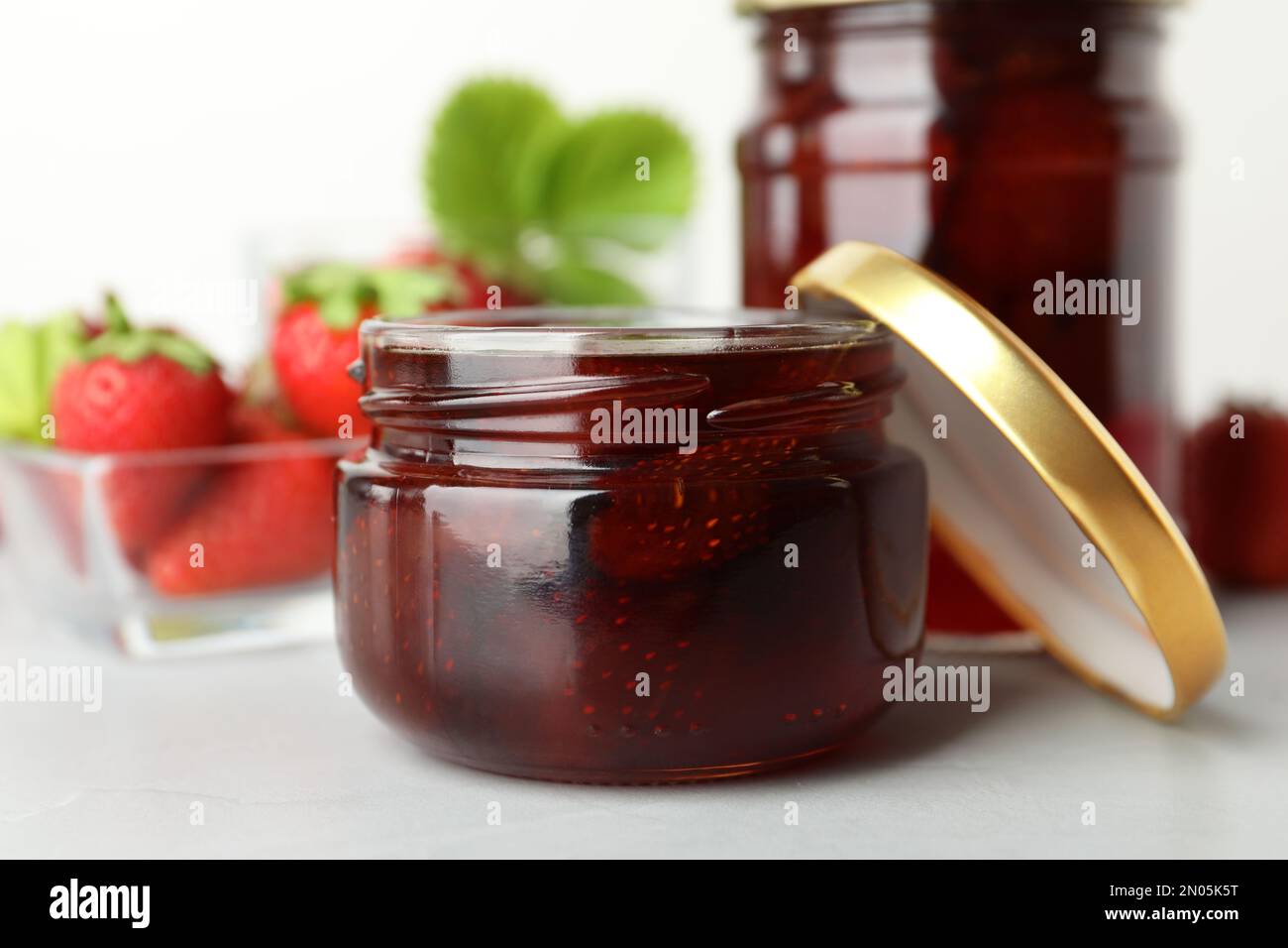 Delicious pickled strawberry jam and fresh berries on light table Stock ...