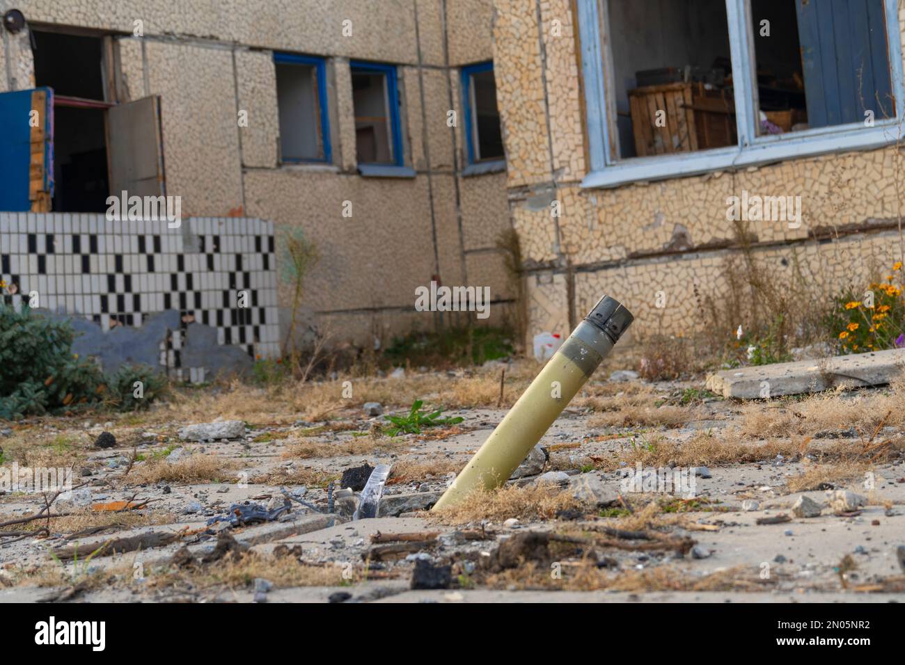 Unexploded rocket projectile sticks out in the ground near the house ...