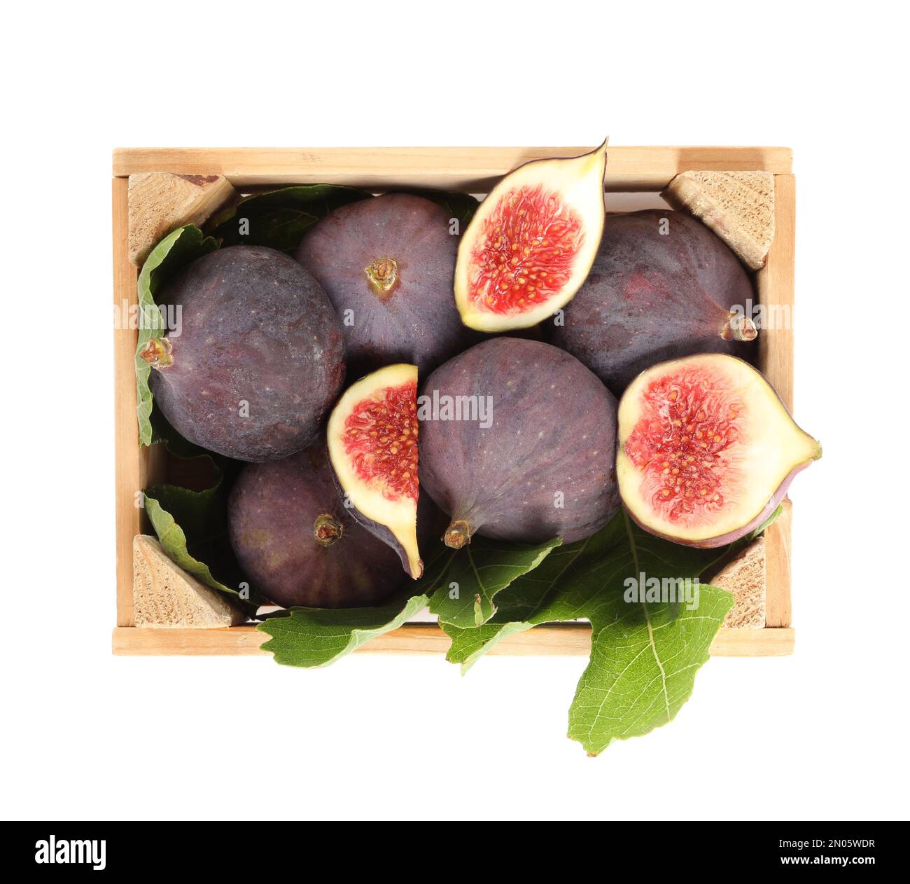 Whole and cut tasty fresh figs with green leaves in wooden crate on ...
