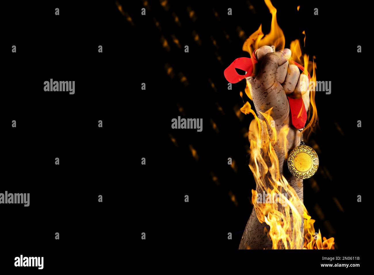 Winner raising hand with gold medal from fire flames on black ...