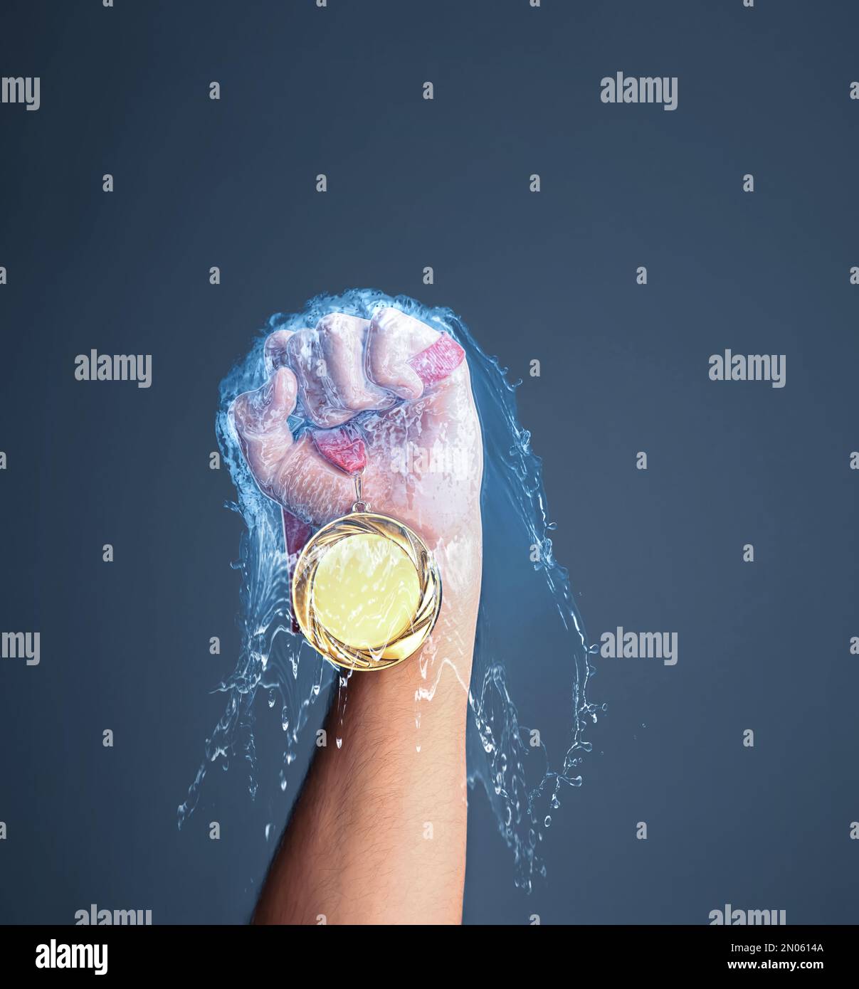 Winner raising hand with gold medal through water splash on dark grey ...