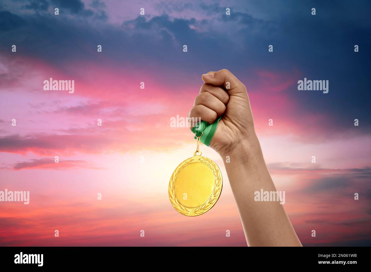 Winner raising hand with gold medal up to sunset sky, closeup Stock ...