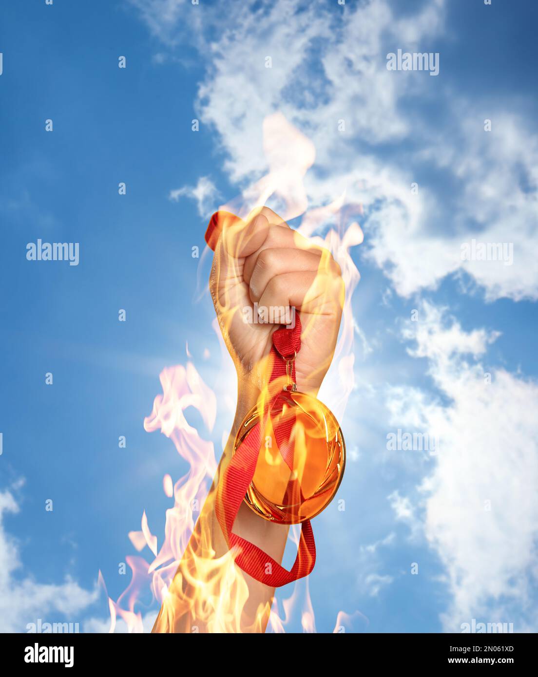 Winner raising hand with gold medal from fire flames up to sky, closeup ...