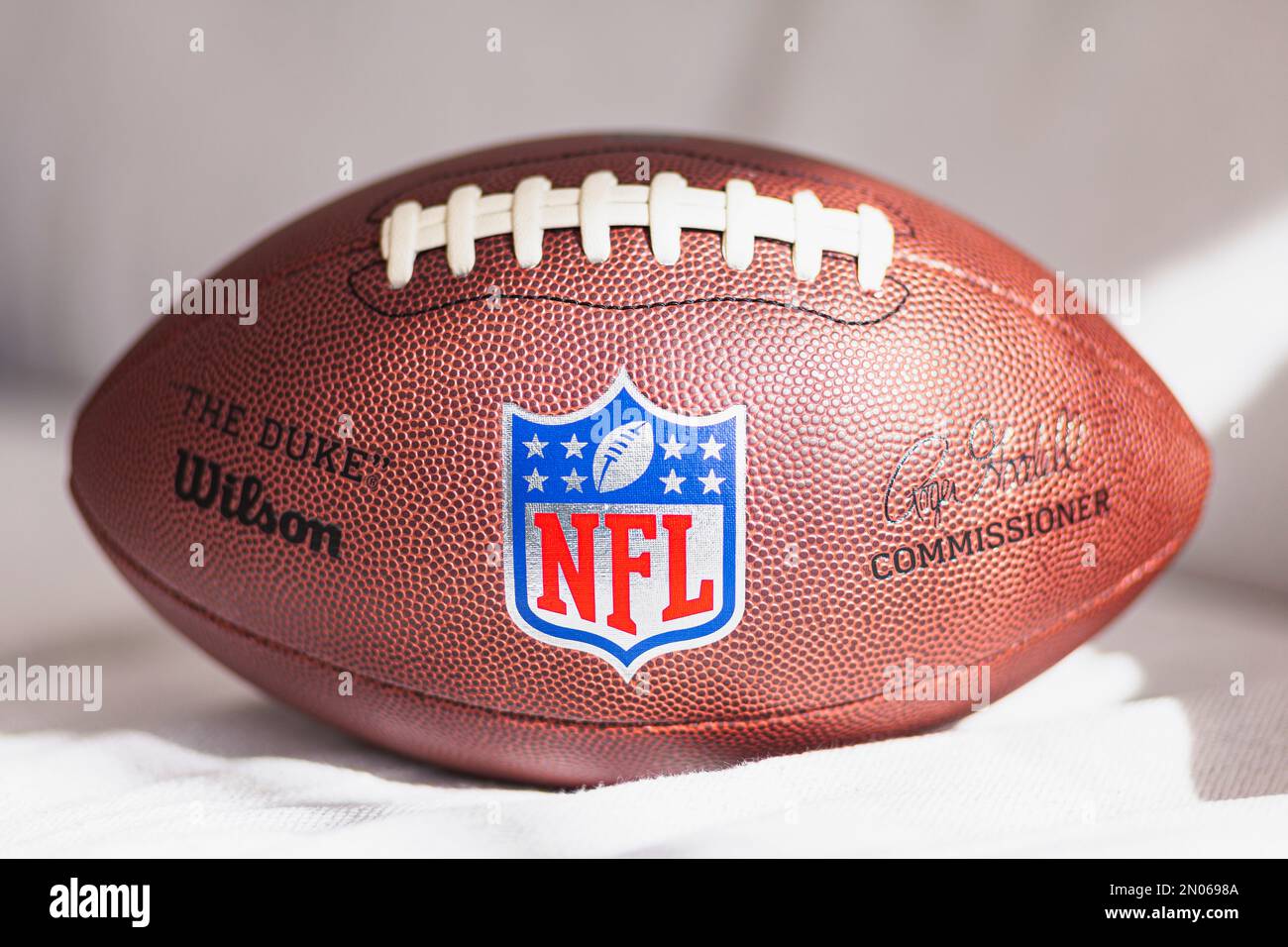 NFL Wilson Duke ball over a white sofa in a home. Sun light comes from ...