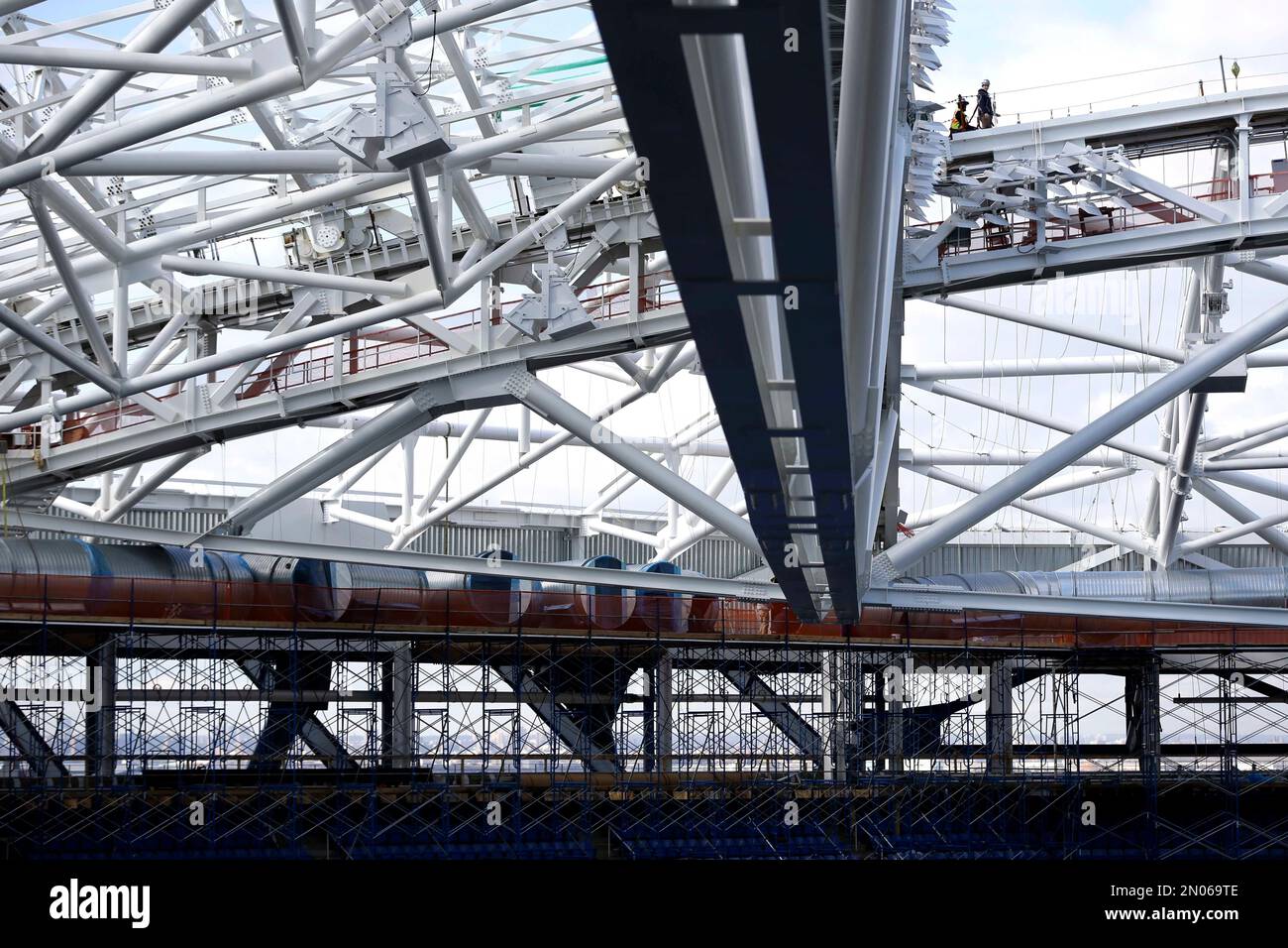 Construction workers traverse a girder as they work on the retractable ...