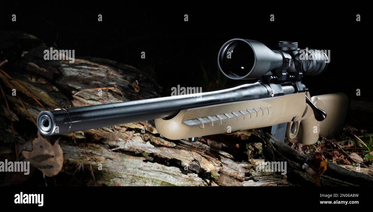 High powered bolt action rifle with a scope in the woods before dawn ...