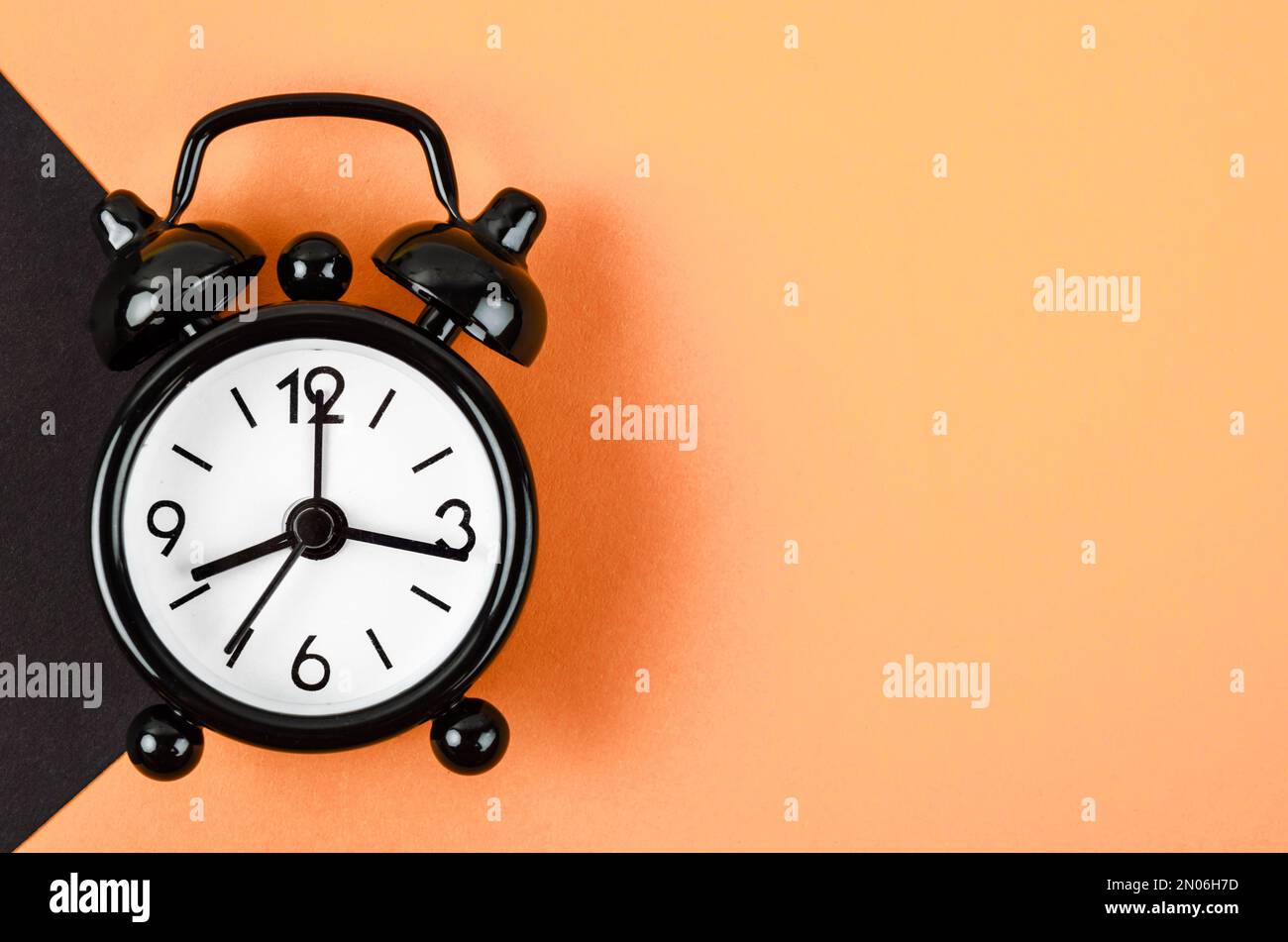 Black vintage alarm clock on paper background with empty space for your ...