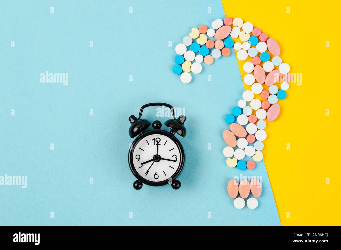 Question mark from laid out of medicine pills with Alarm Clock on blue ...