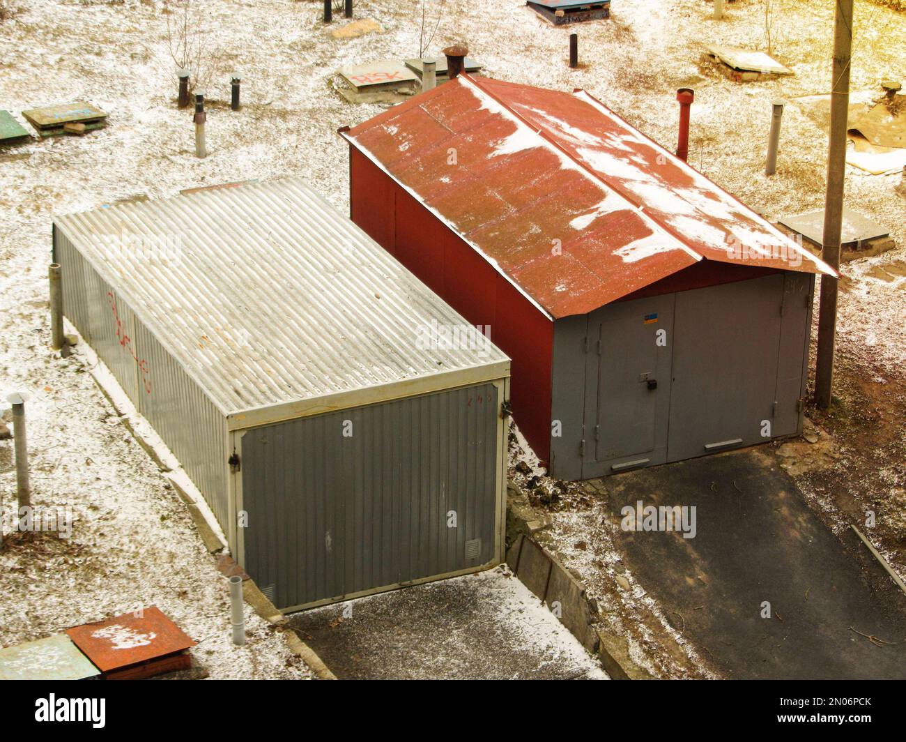 Two old metal car garages as seen from above in winter. One old gray ...
