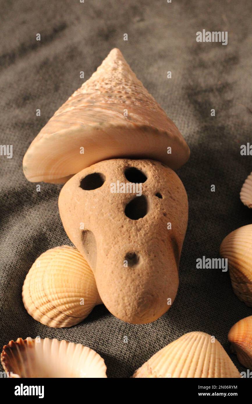 A vertical closeup of a small clay figure with multiple shells on a a ...