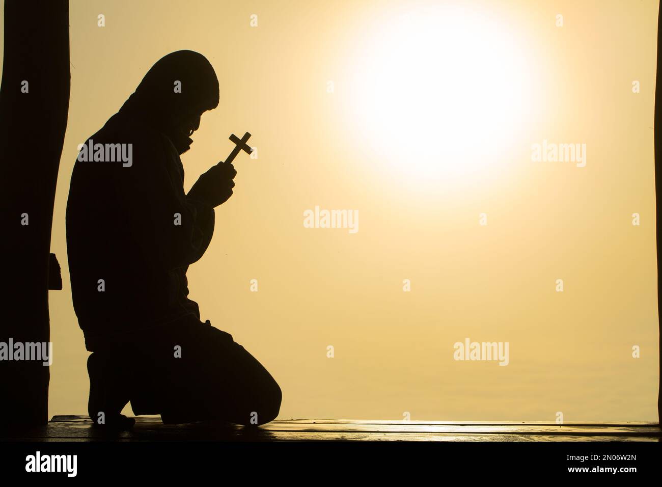 Silhouette of christian Man holding a cross cross in hands praying for ...