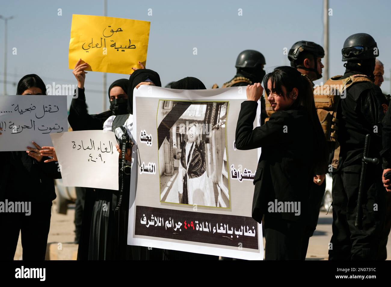 Demonstrators hold placards and a poster with a picture of Tiba Ali, a ...