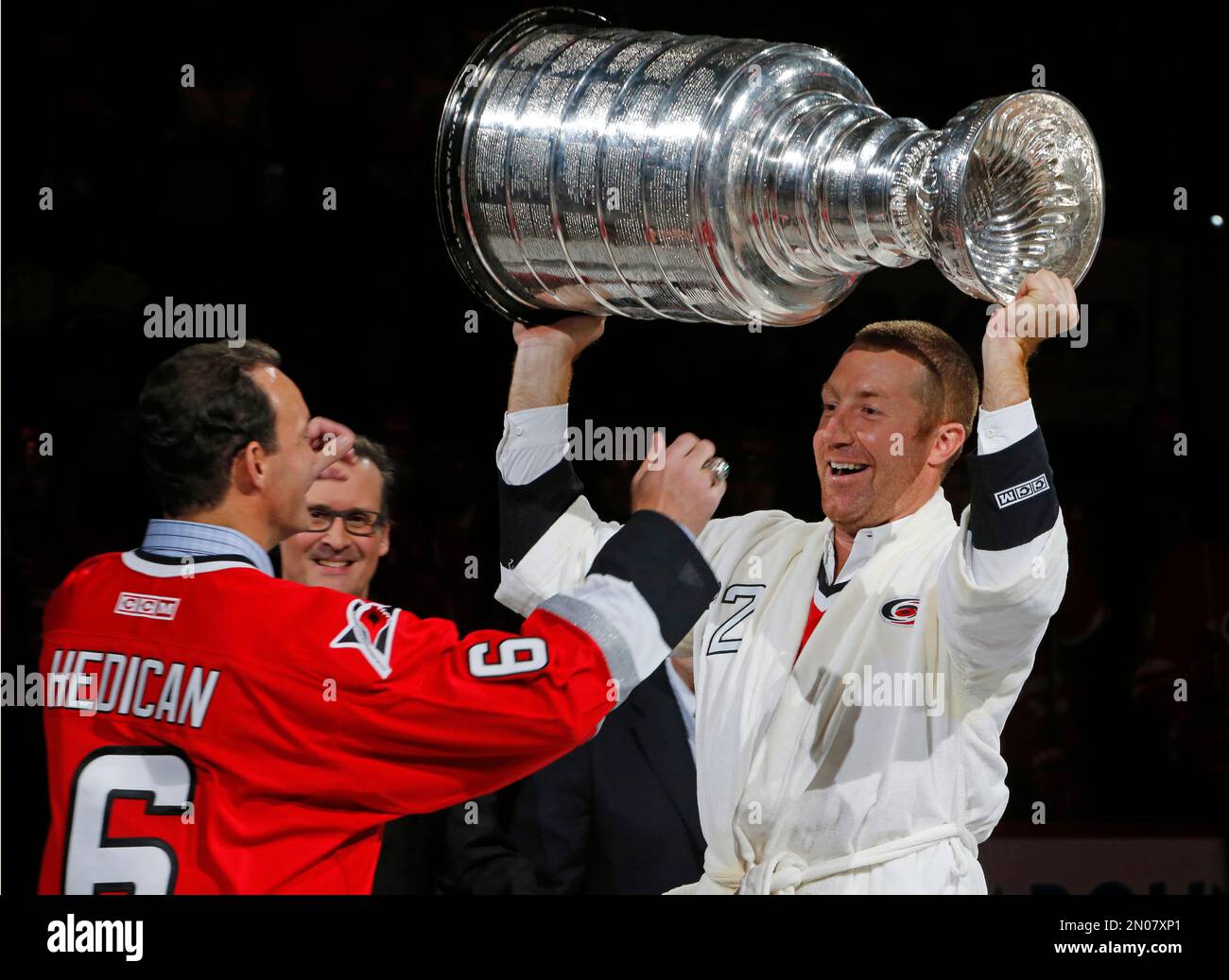 Former Carolina Hurricane Bret Hedican, left, is passed the Stanley Cup by former teammate Mike ...