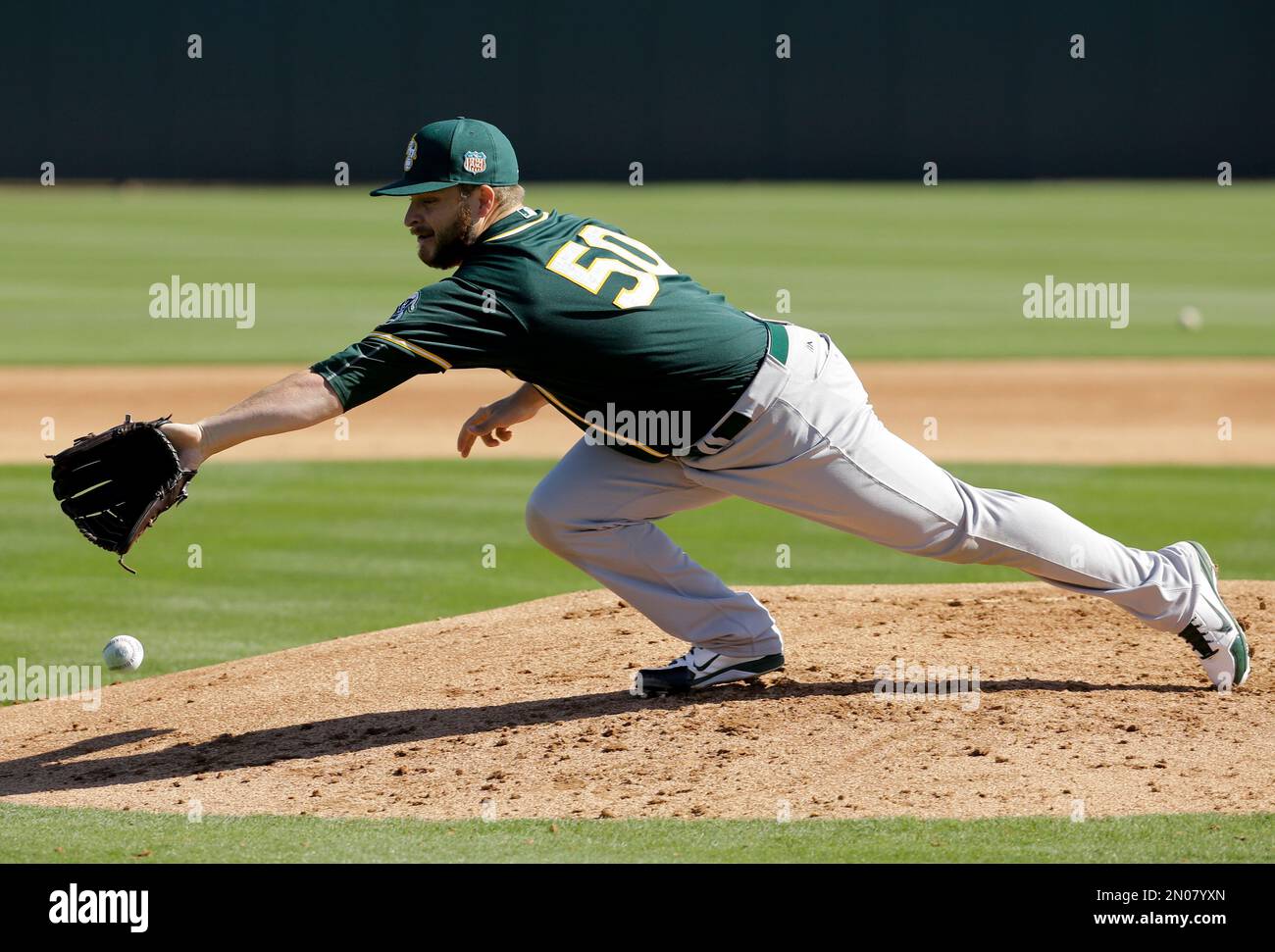 Oakland Athletics relief pitcher Ryan Brasier reaches for a ball during ...