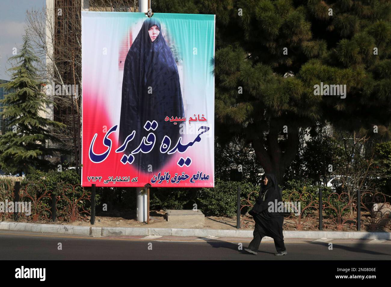 An Iranian woman walks past an electoral banner of Hamideh Ghadiri, a ...
