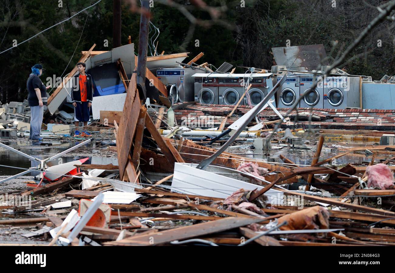 Spectators walk through debris left by a deadly storm that swept ...