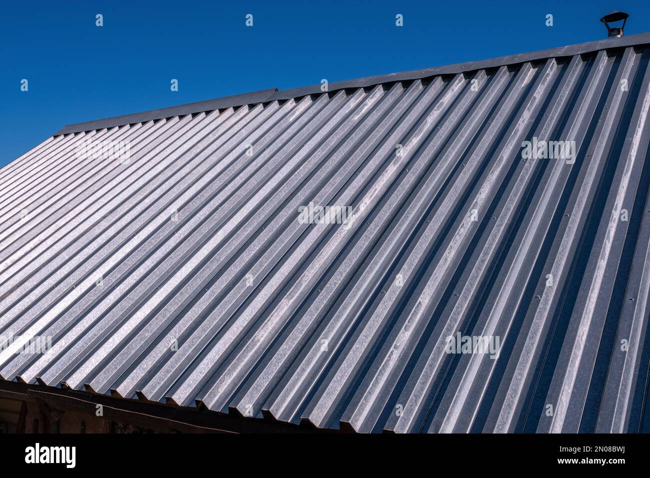 Metal roof constructed from galvanized iron sheets on the background of ...