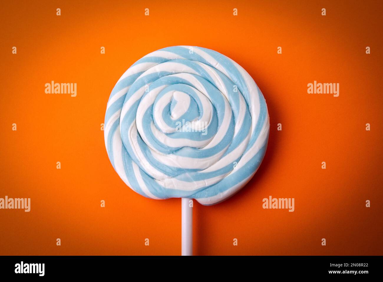 Blue and white candy on a stick, lollipop. Orange background Stock ...