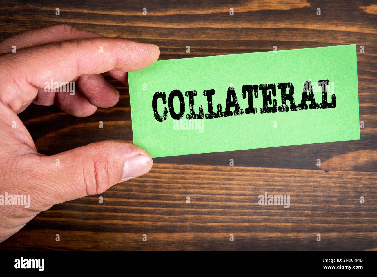 Collateral. Text on green sticky note. Wood texture background Stock ...
