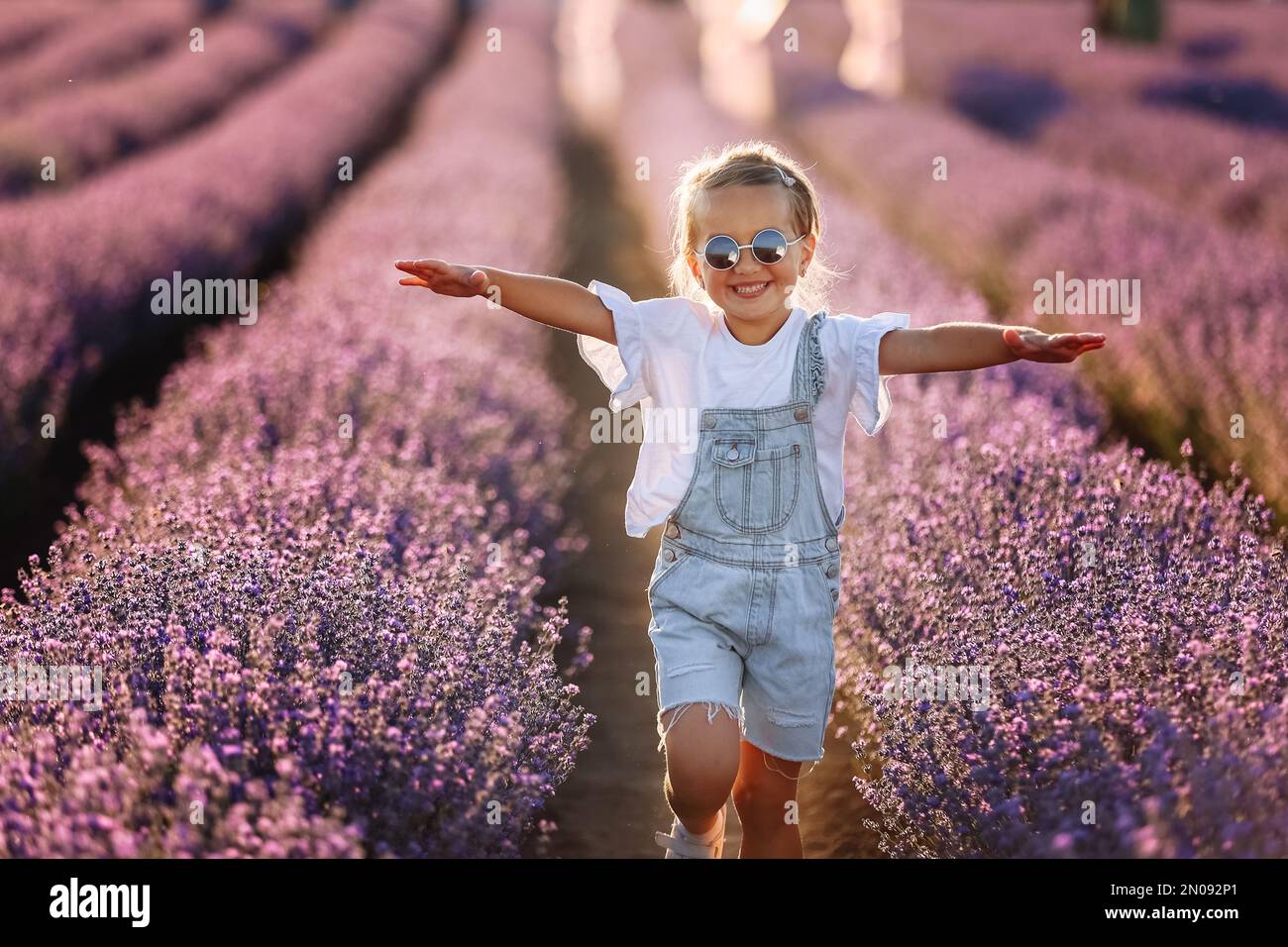 Adorable happy child girl runs raising her hands like flying plane in ...