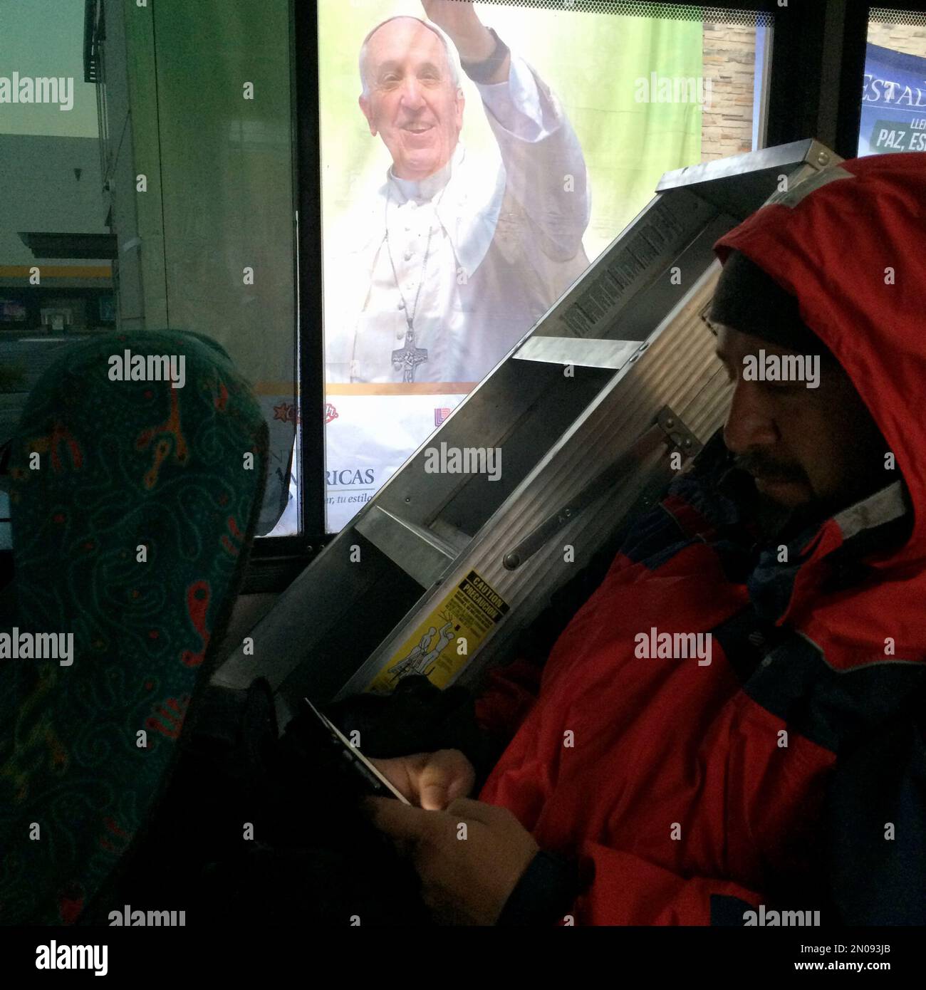 A photographer sitting beside his ladder uses his cell phone inside a ...