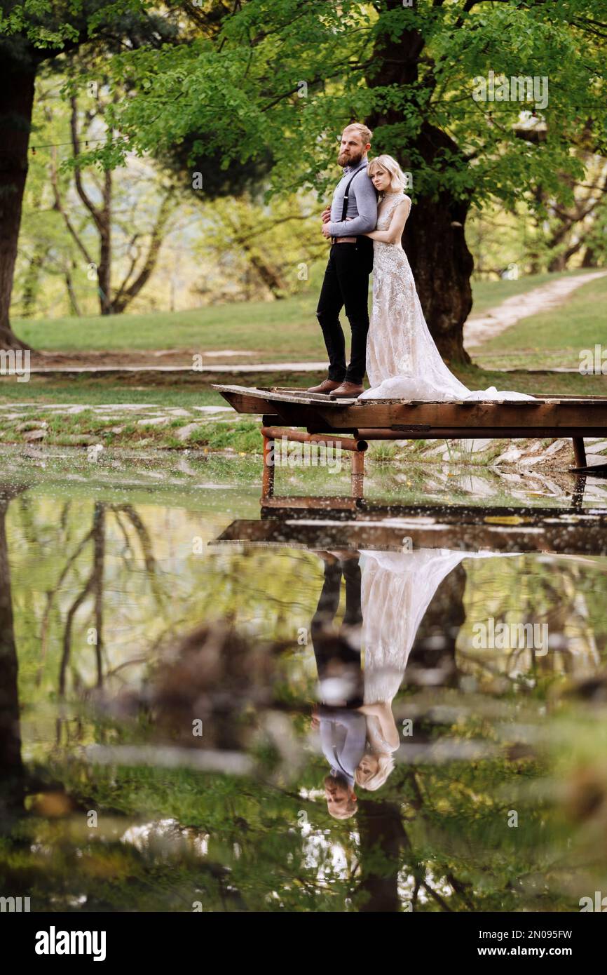 Beautiful, cheerful and lively newlyweds, groom and bride are hugging ...