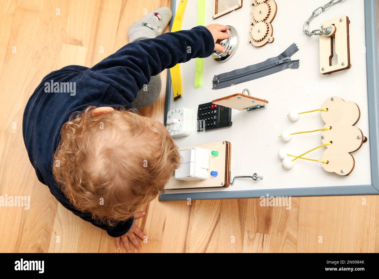 The small child plays with the activity board to get new experience ...