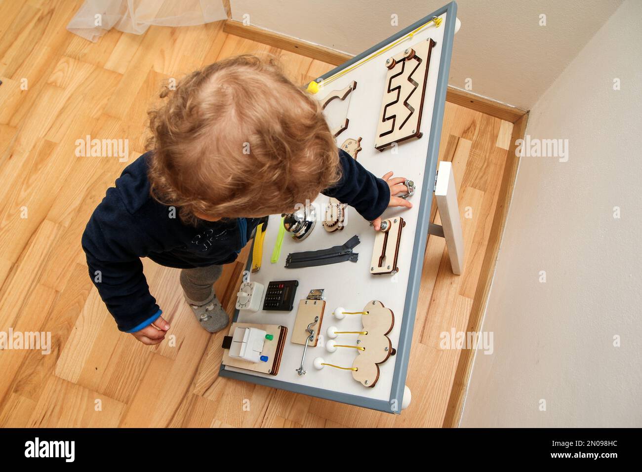 The small child plays with the activity board to get new experience ...
