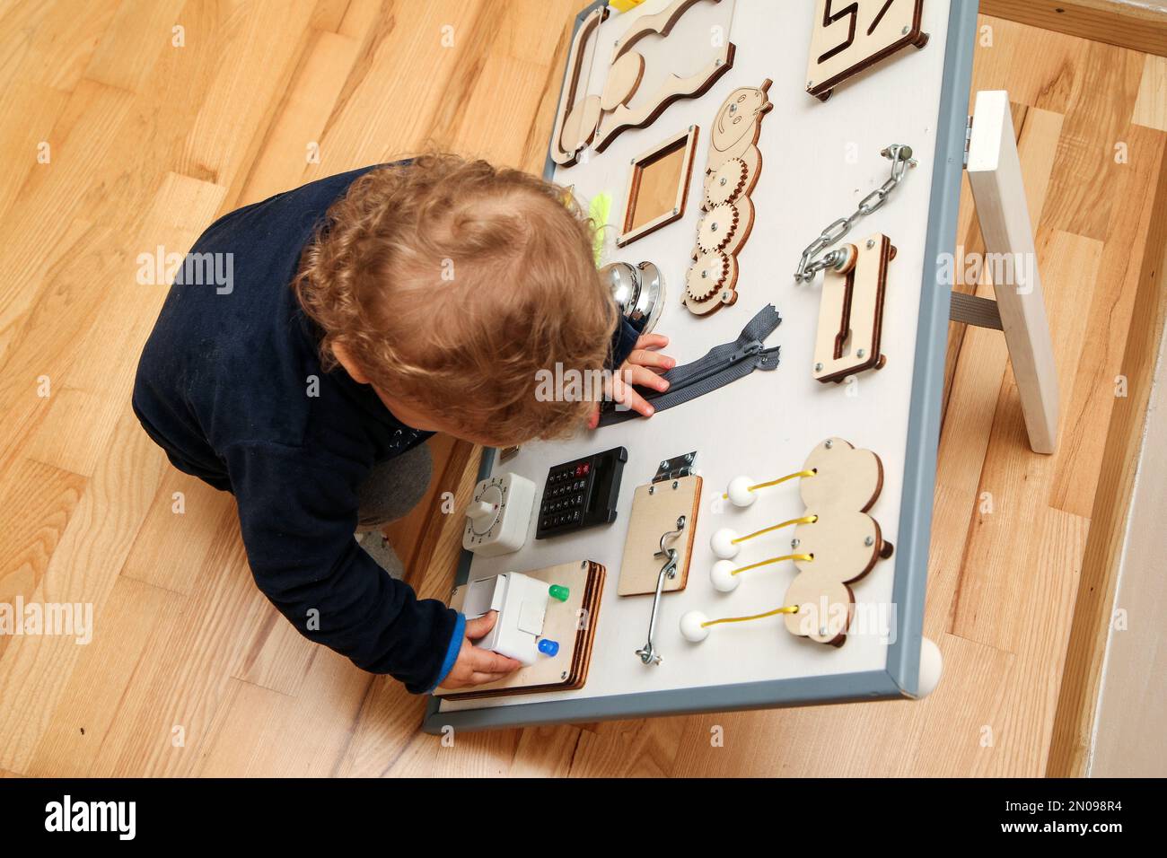 The small child plays with the activity board to get new experience ...