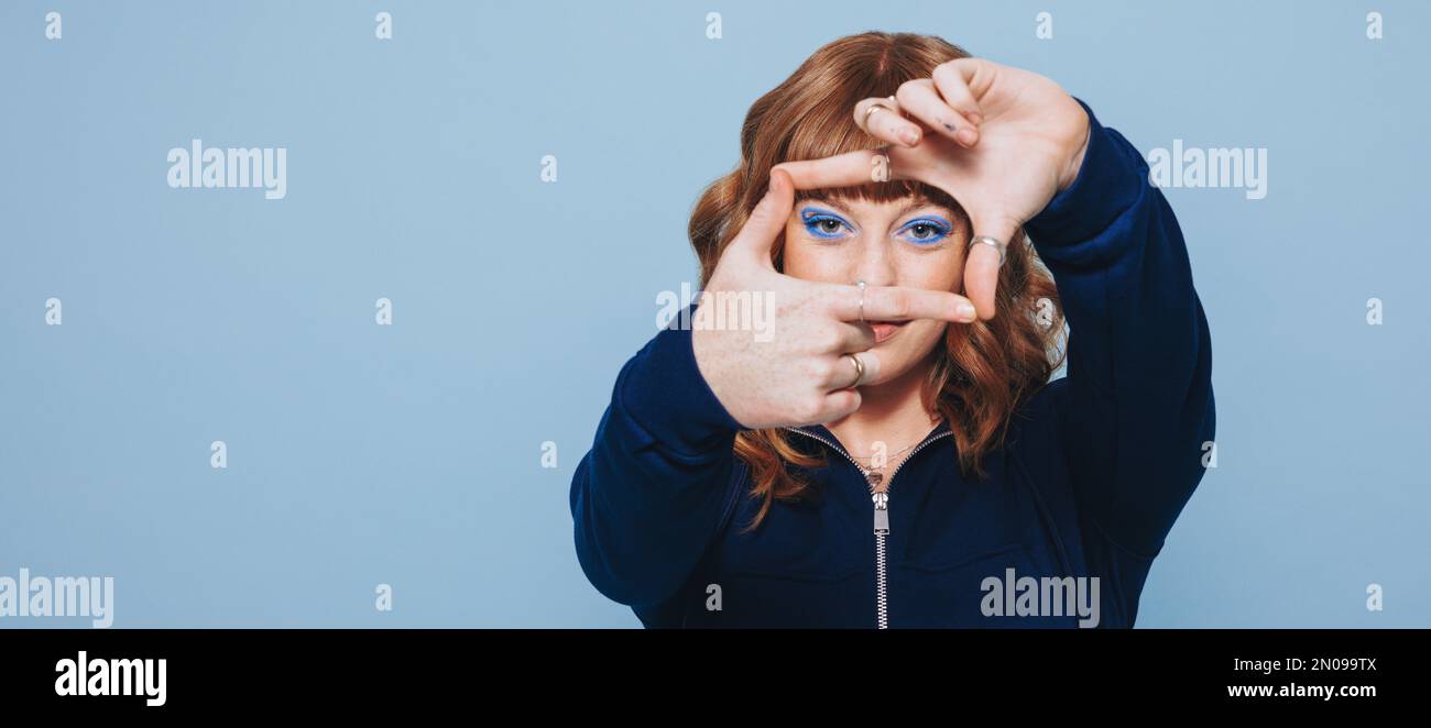 Woman looking at the camera while making a finger frame. Young woman ...