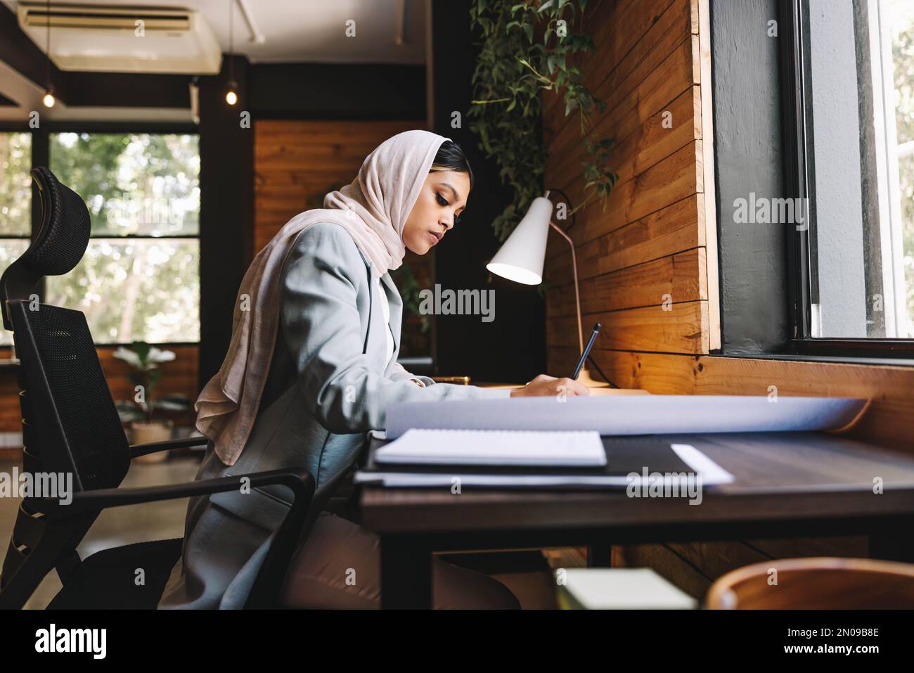 Muslim designer making new architectural drawings in a modern office. Creative young ...