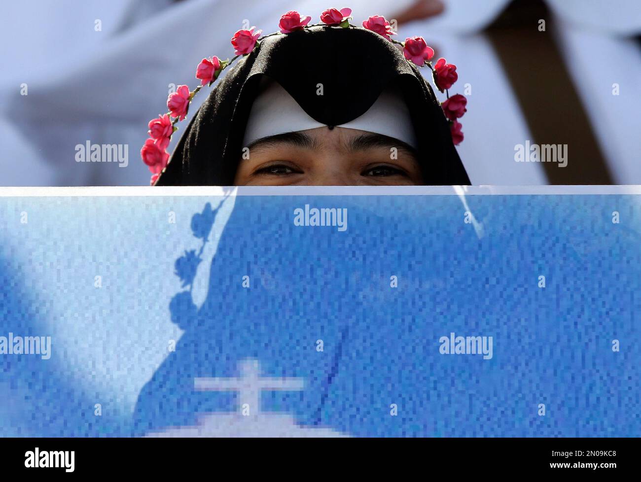 A nun smiles behind a poster welcoming Pope Francis to Venustiano ...