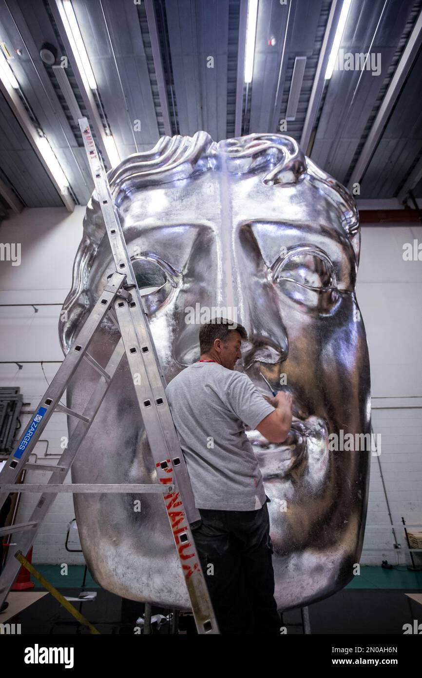 A set builder works on a giant replica of the British Academy Films ...