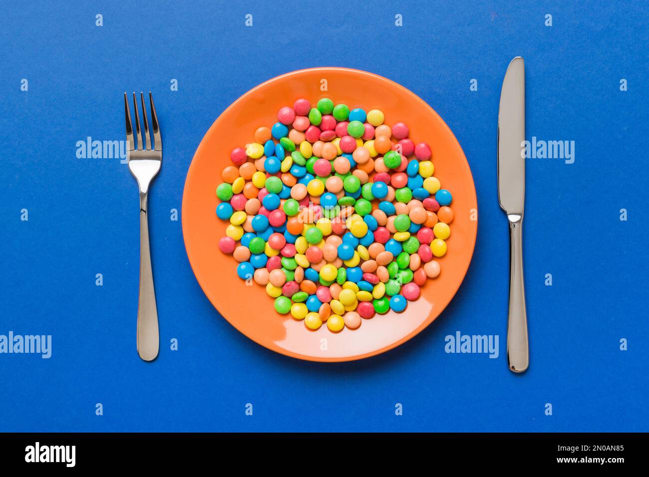 cutlery on table and sweet plate of candy. Health and obesity concept ...