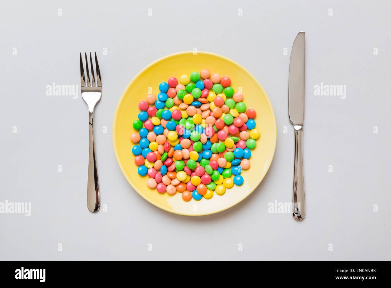 cutlery on table and sweet plate of candy. Health and obesity concept ...