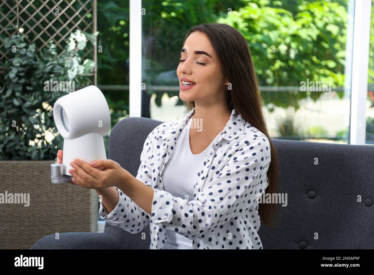 Woman enjoying air flow from portable fan at home. Summer heat Stock ...