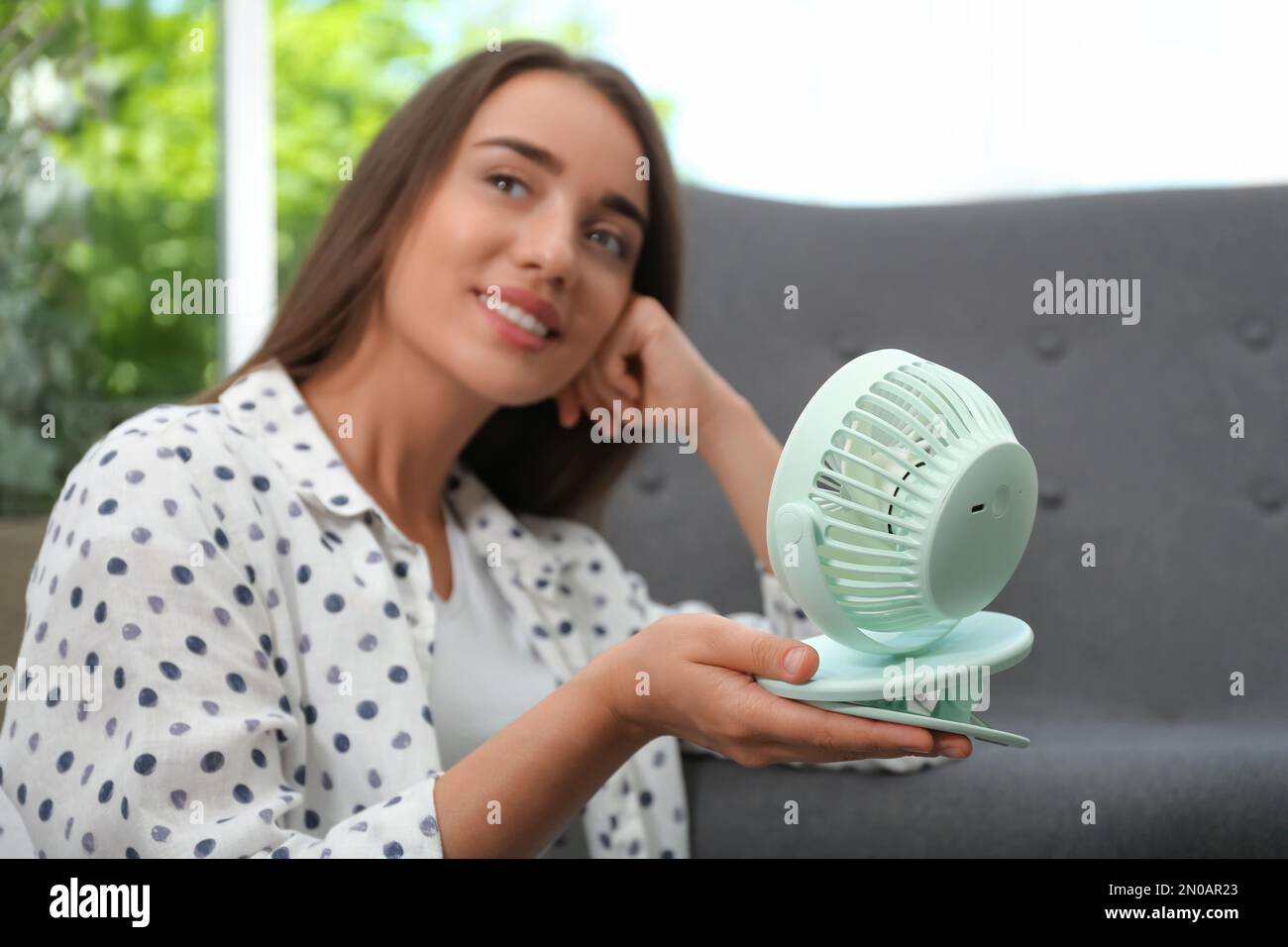 Woman enjoying air flow from portable fan at home. Summer heat Stock ...