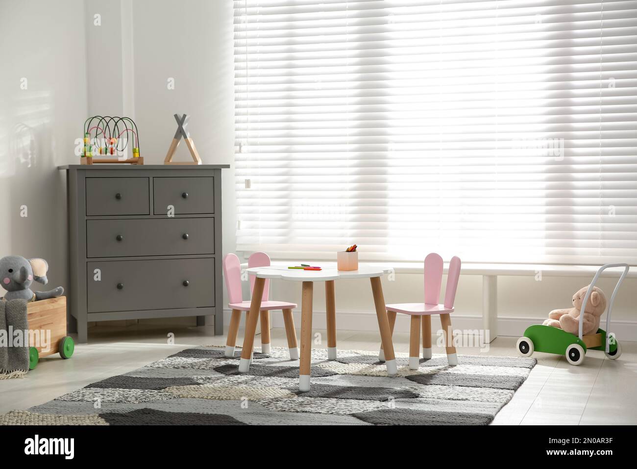 Little table and chairs with bunny ears near window in children's room ...