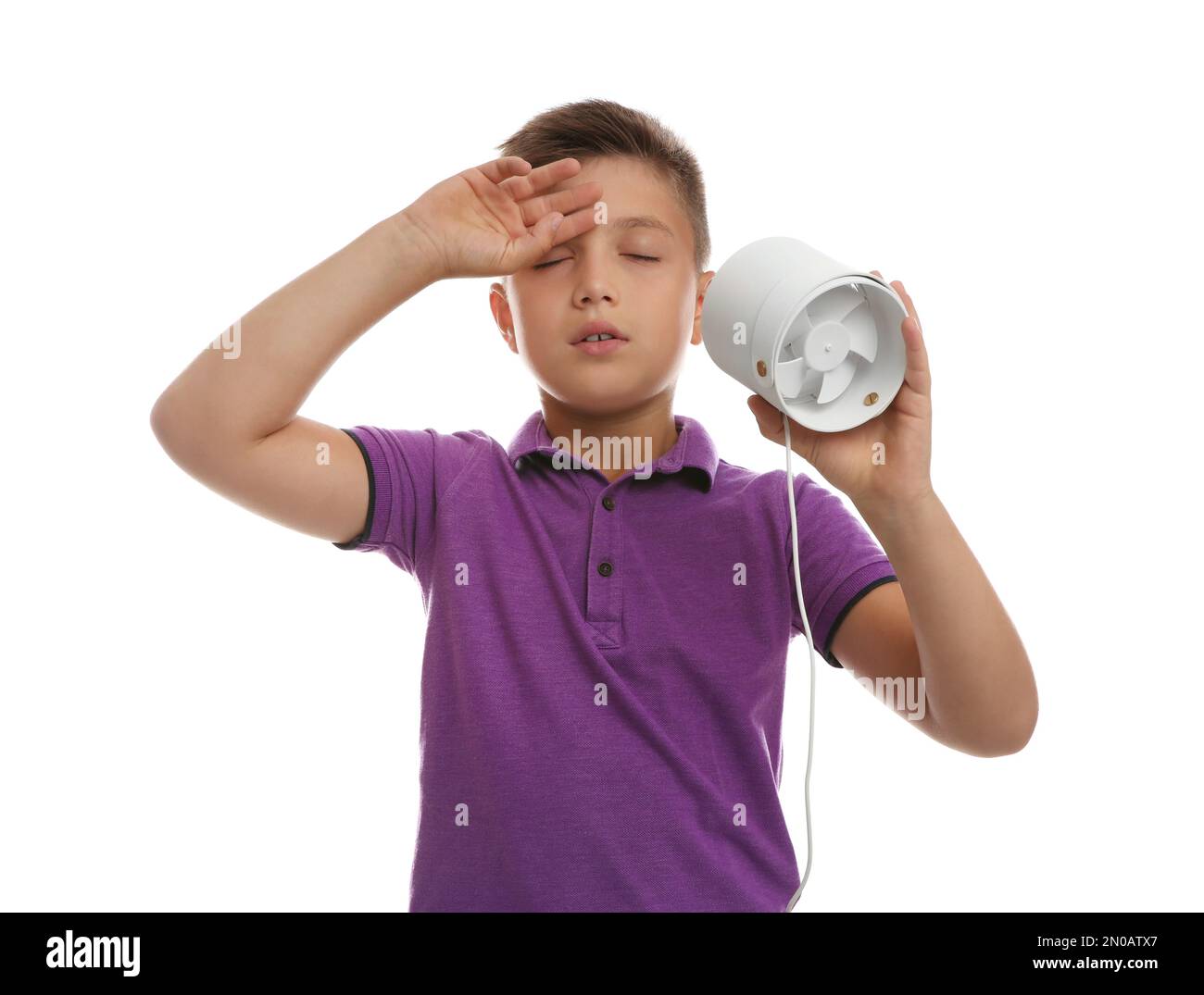 Little boy with portable fan suffering from heat on white background ...